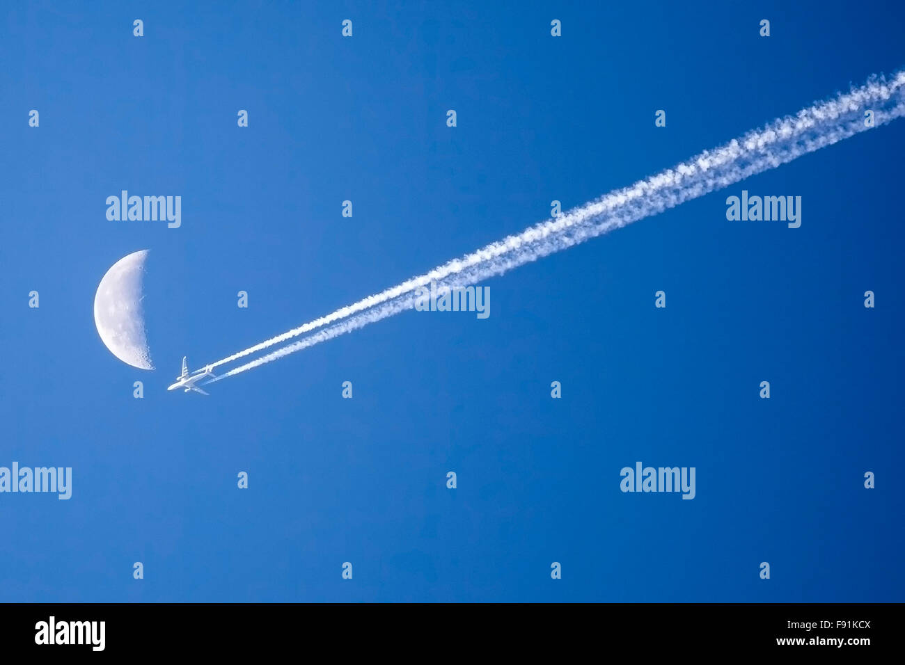 Airplane Flying Past The Moon Against Bright Blue Sky Stock Photo - Alamy