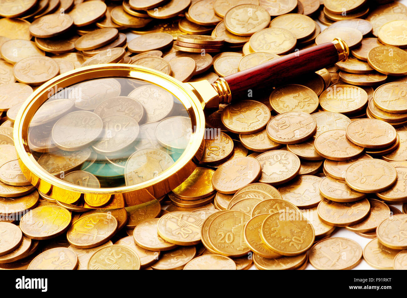 Magnifying glass and coins at the background Stock Photo - Alamy