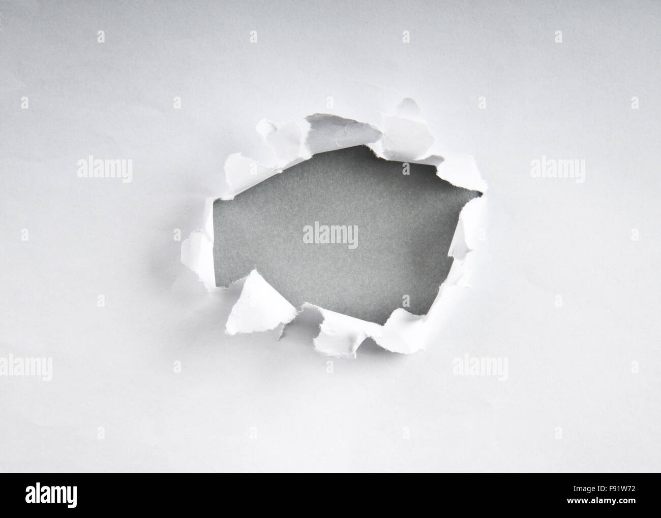 Hole in the paper with torn sides Stock Photo - Alamy