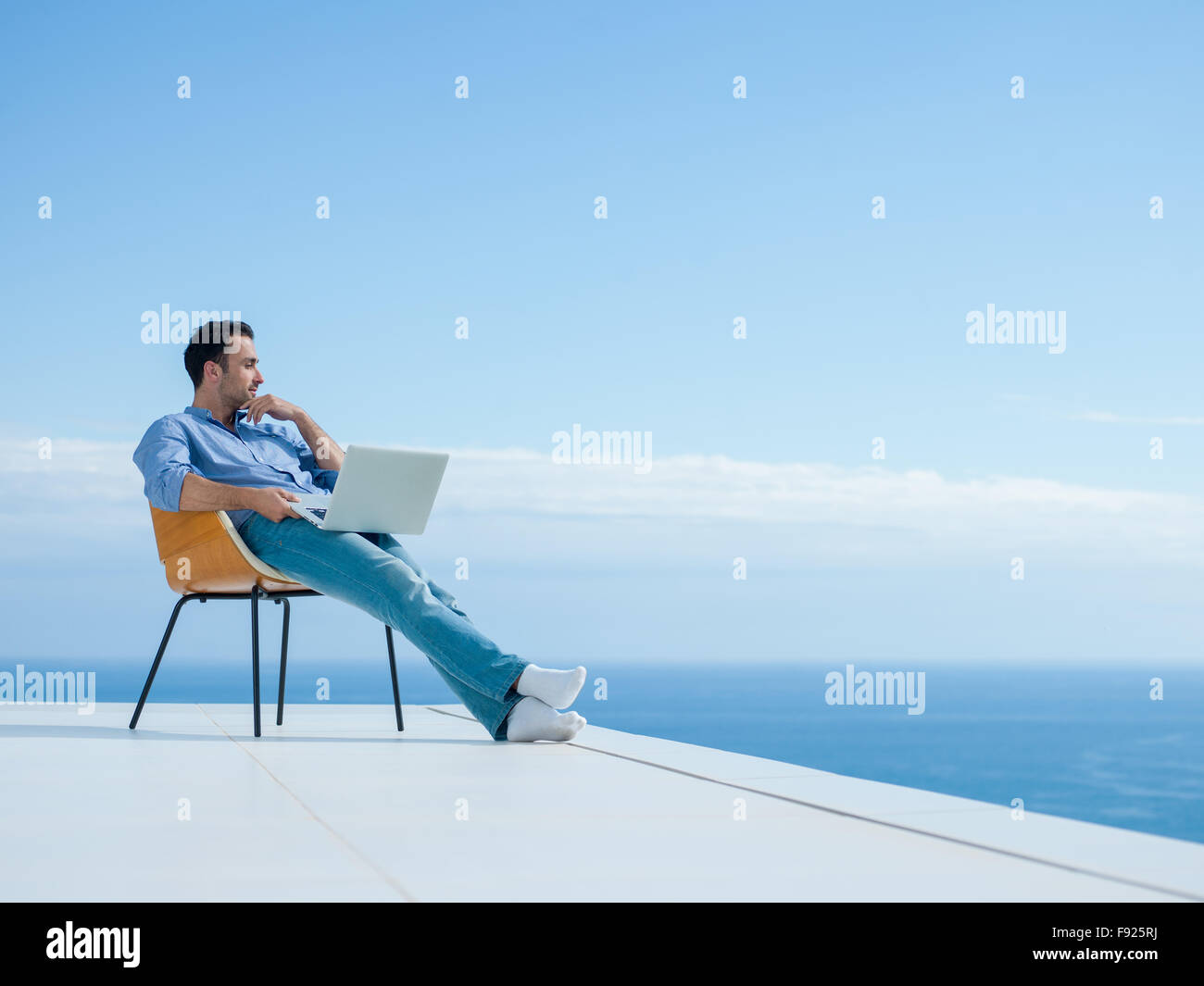 handsome young man relaxing and working on laptop computer at home ...