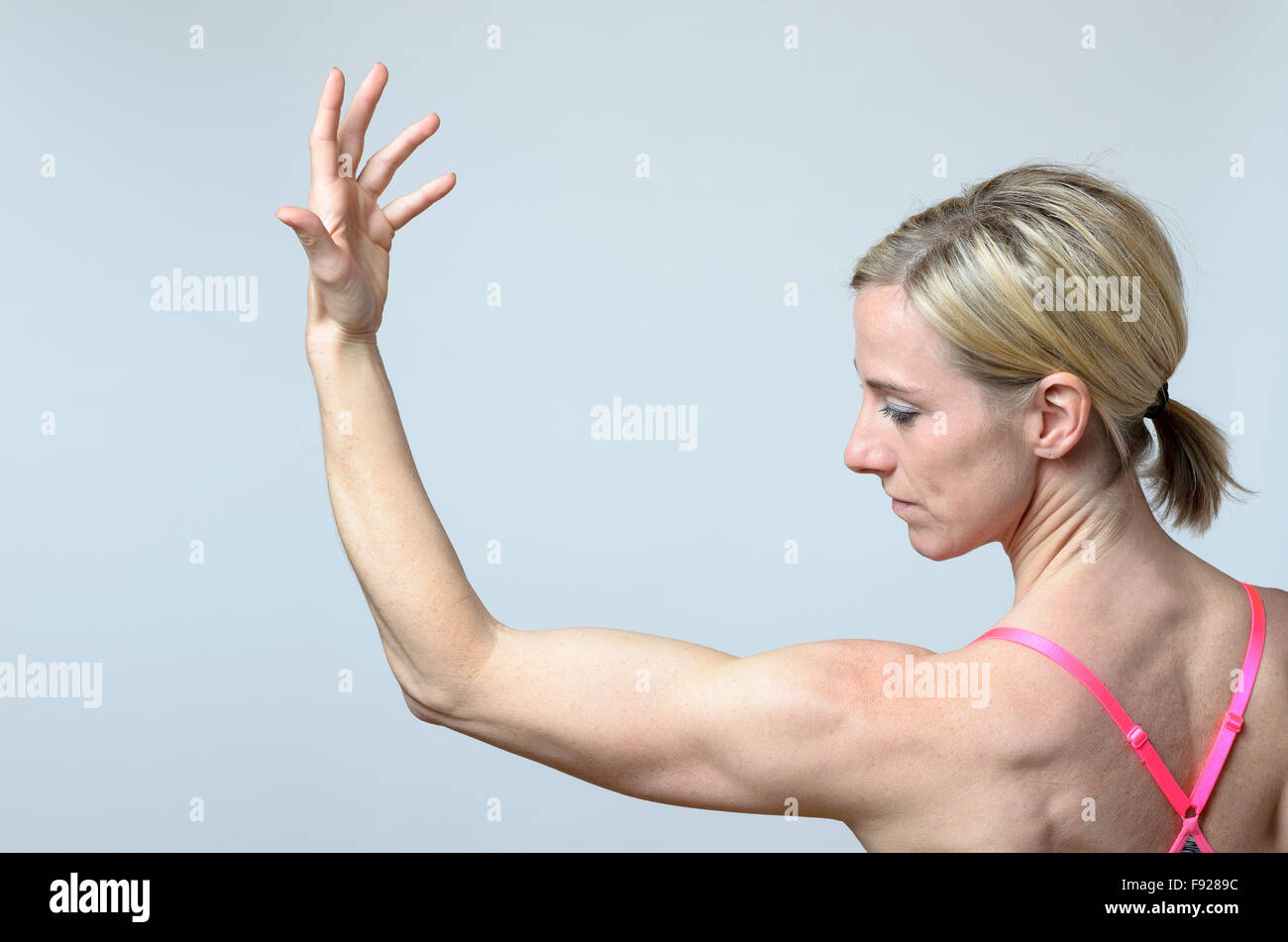 Back of an attractive woman bodybuilder showing off her biceps as she ...