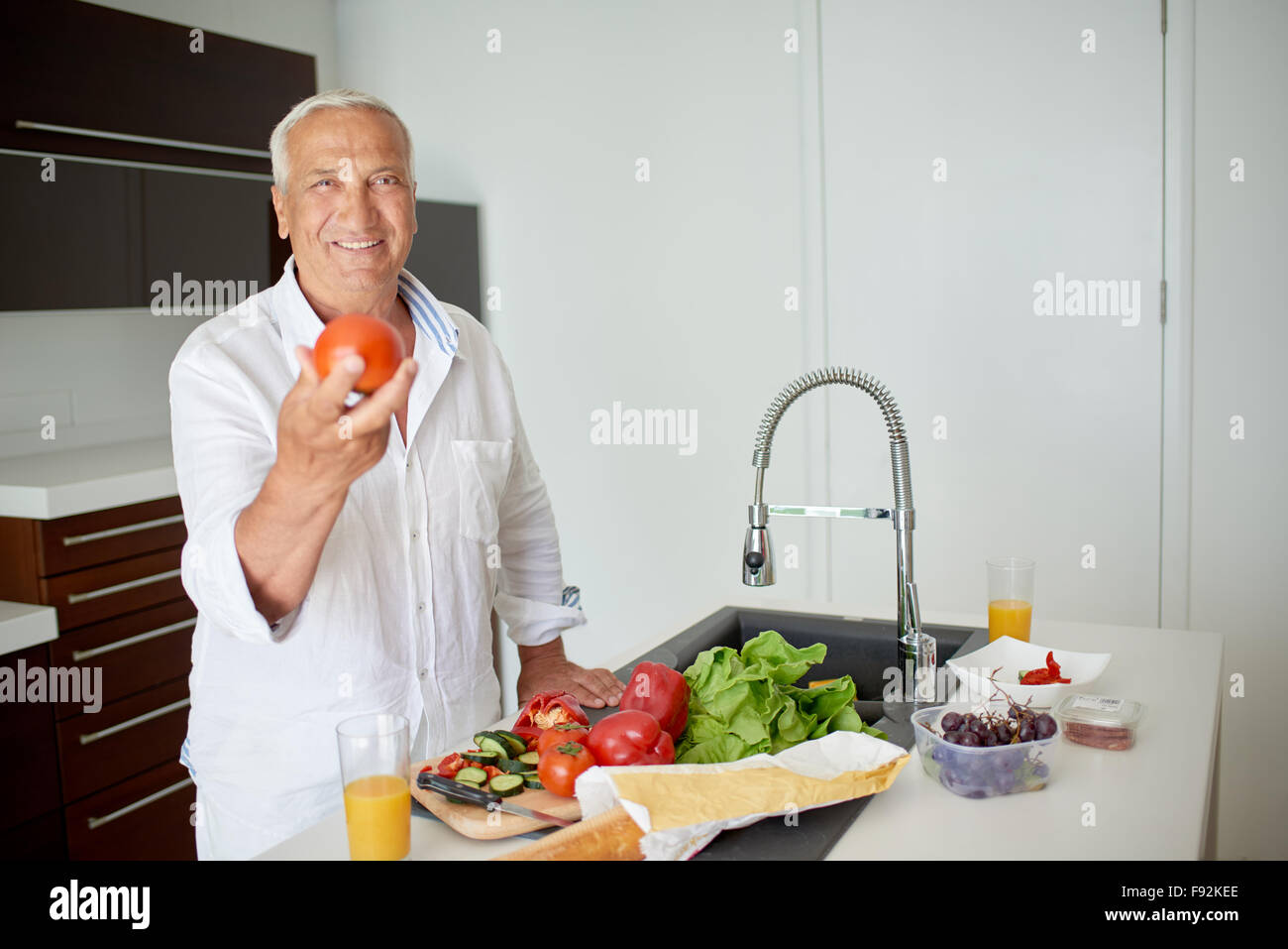Handsome man cooking at home preparing salad in kitchen Stock Photo - Alamy