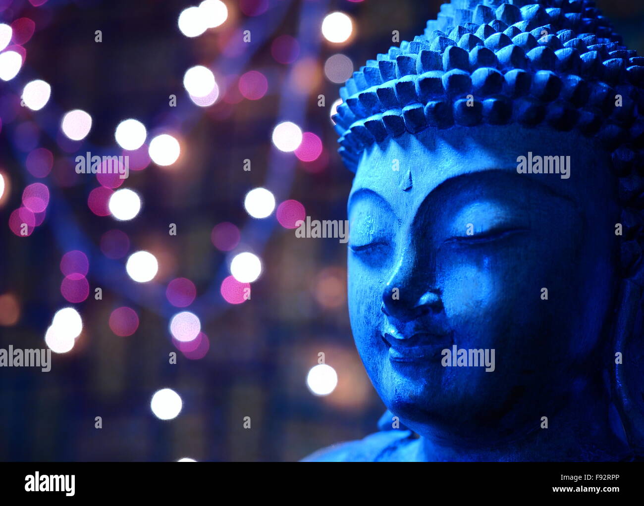 Blue Buddha face with blurred lights in the backgound Stock Photo - Alamy