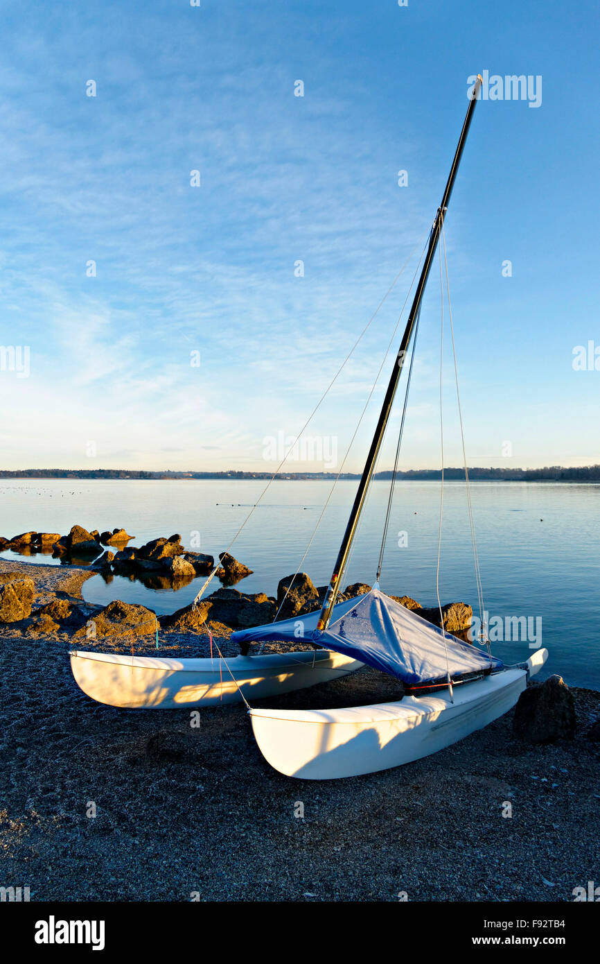 Catamaran sailing boat on beach near waters edge, Lake Chiemsee ...