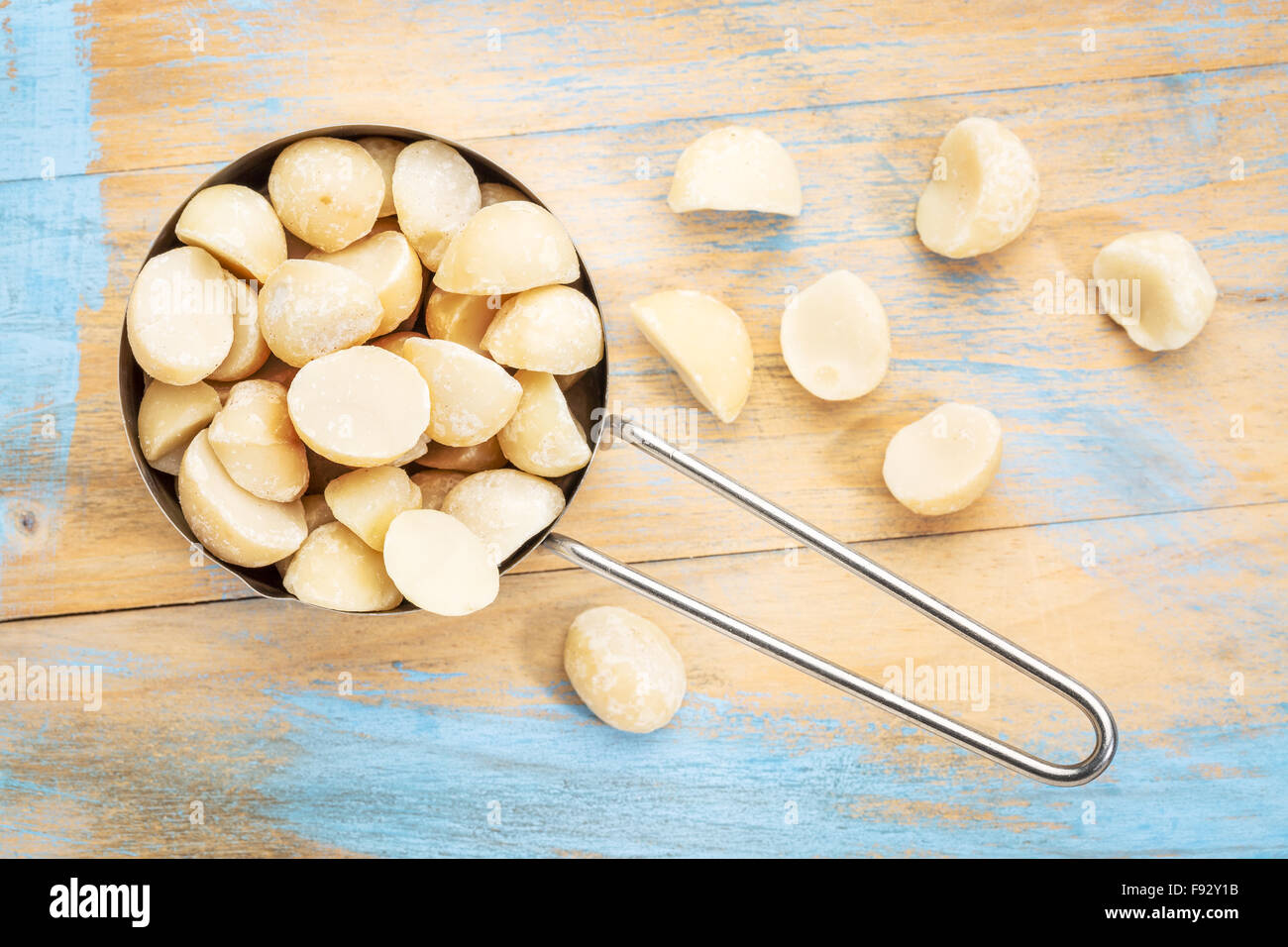 macadamia nuts in a metal measuring scoop (1/2 cup) against rustic barn ...