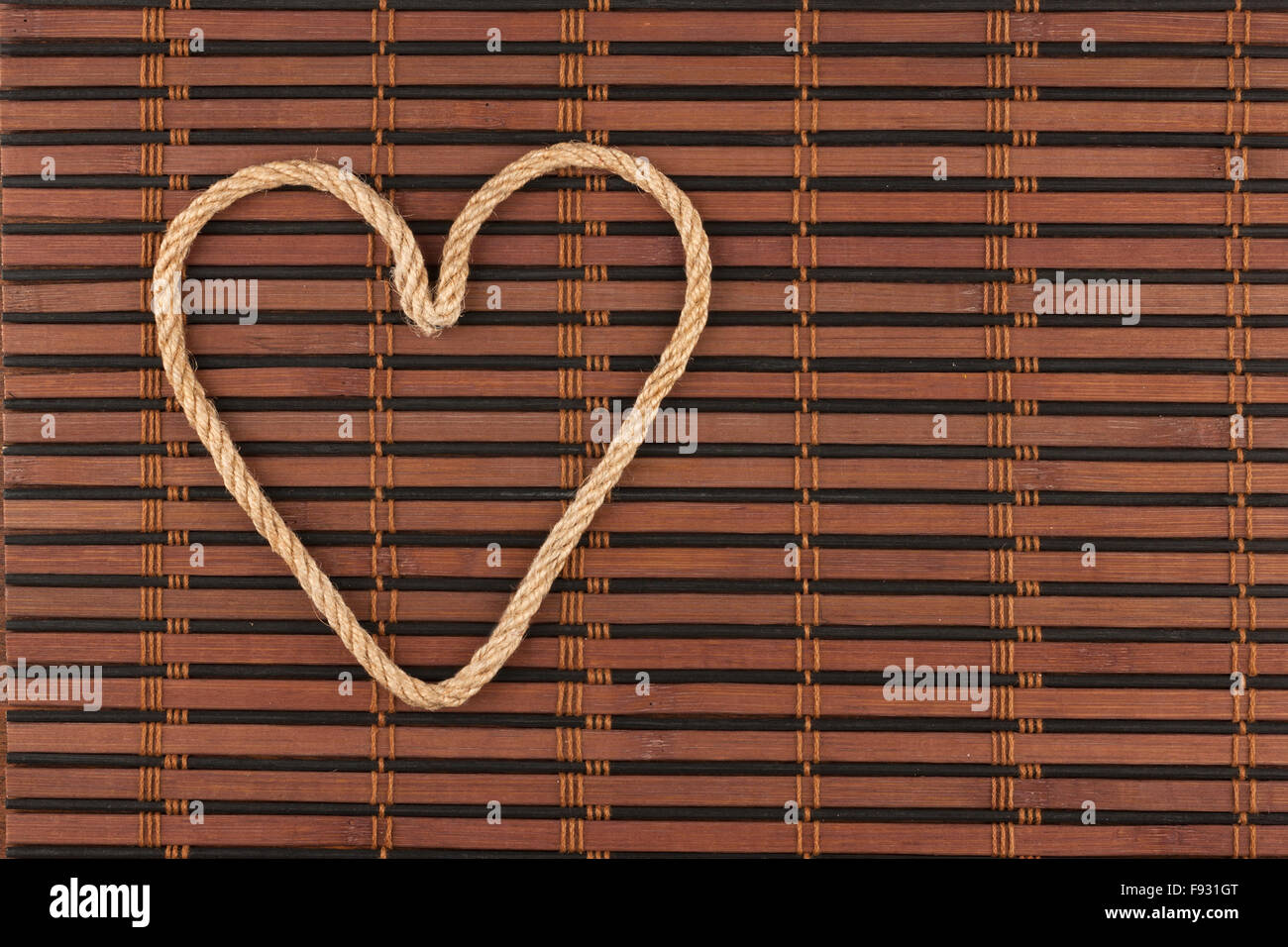 Symbolic heart made of rope lying on a bamboo mat, as background Stock ...