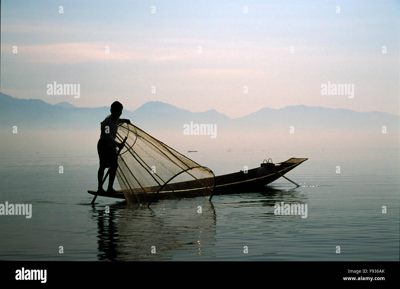 Traditional leg rower with iconic conical fishing net silhouetted ...