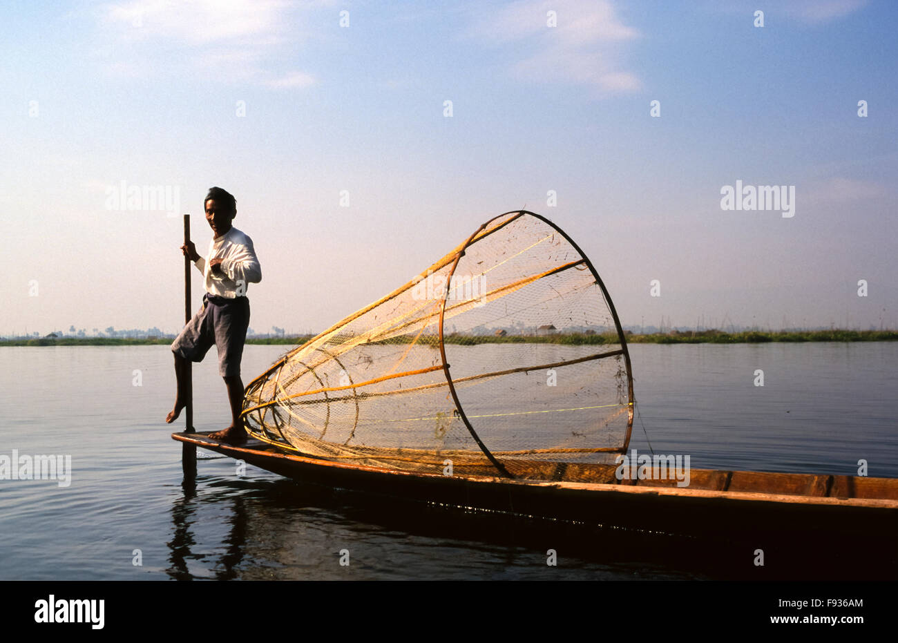 Traditional leg rower with iconic conical fishing net in early morning ...