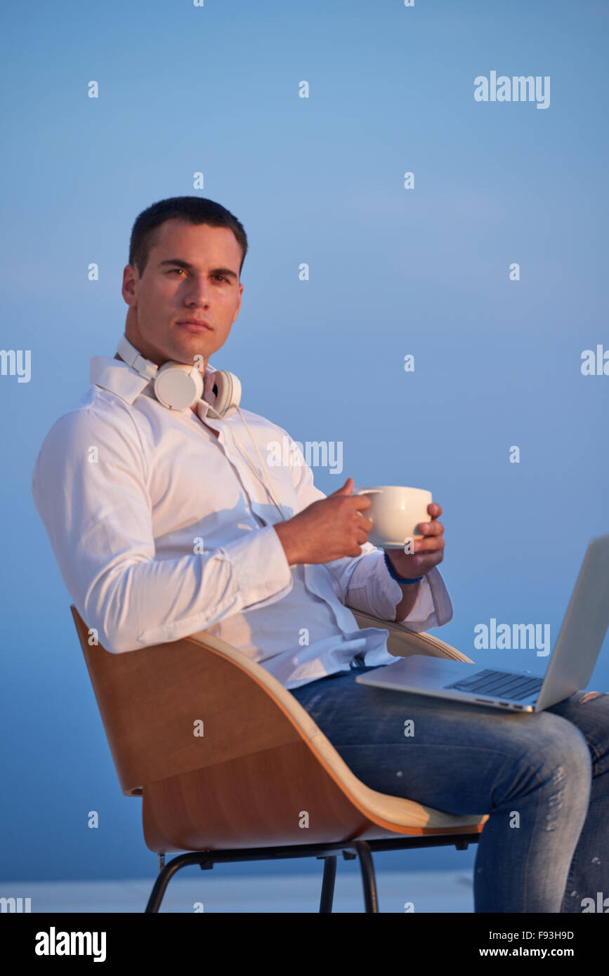 handsome young man relaxing and working on laptop computer at home ...