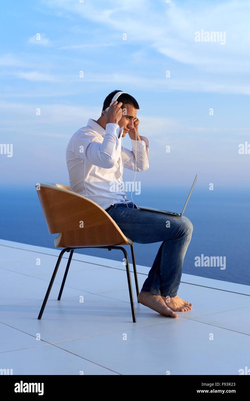 handsome young man relaxing and working on laptop computer at home ...