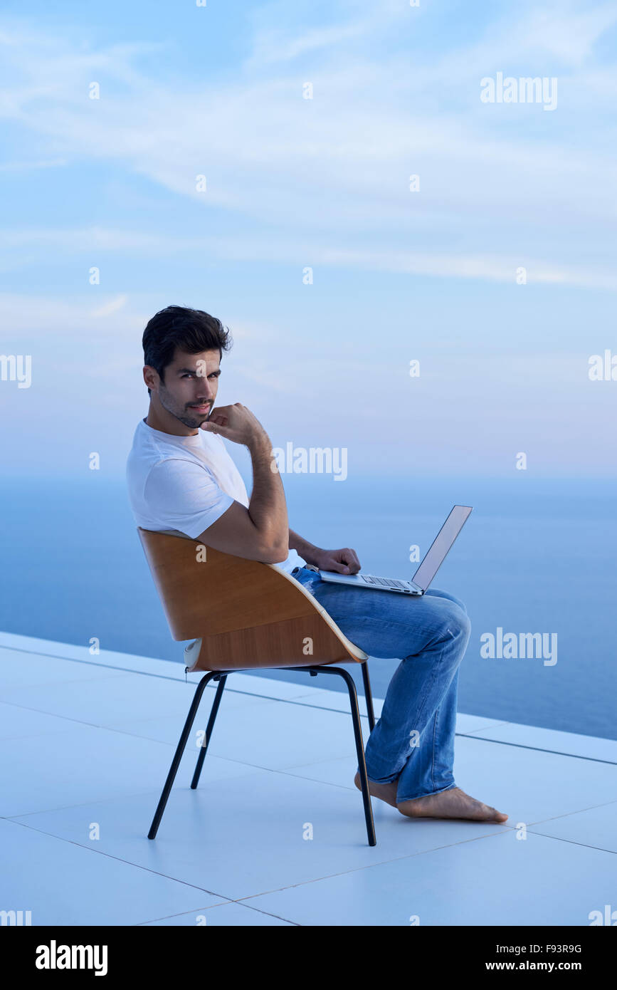 handsome young man relaxing and working on laptop computer at home ...