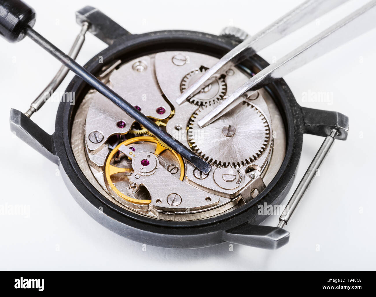 adjusting old mechanic wristwatch - screwdriver and tweezers on open ...