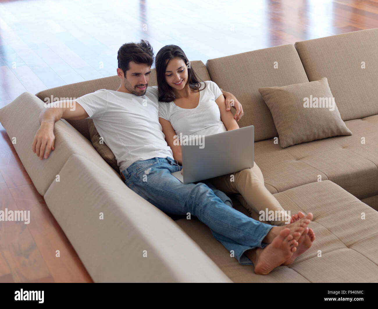 happy young relaxed couple working on laptop computer at modern home ...