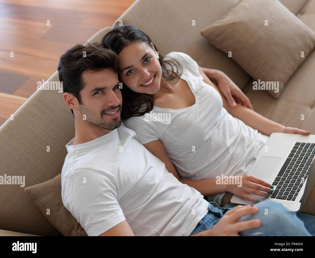 happy young relaxed couple working on laptop computer at modern home ...