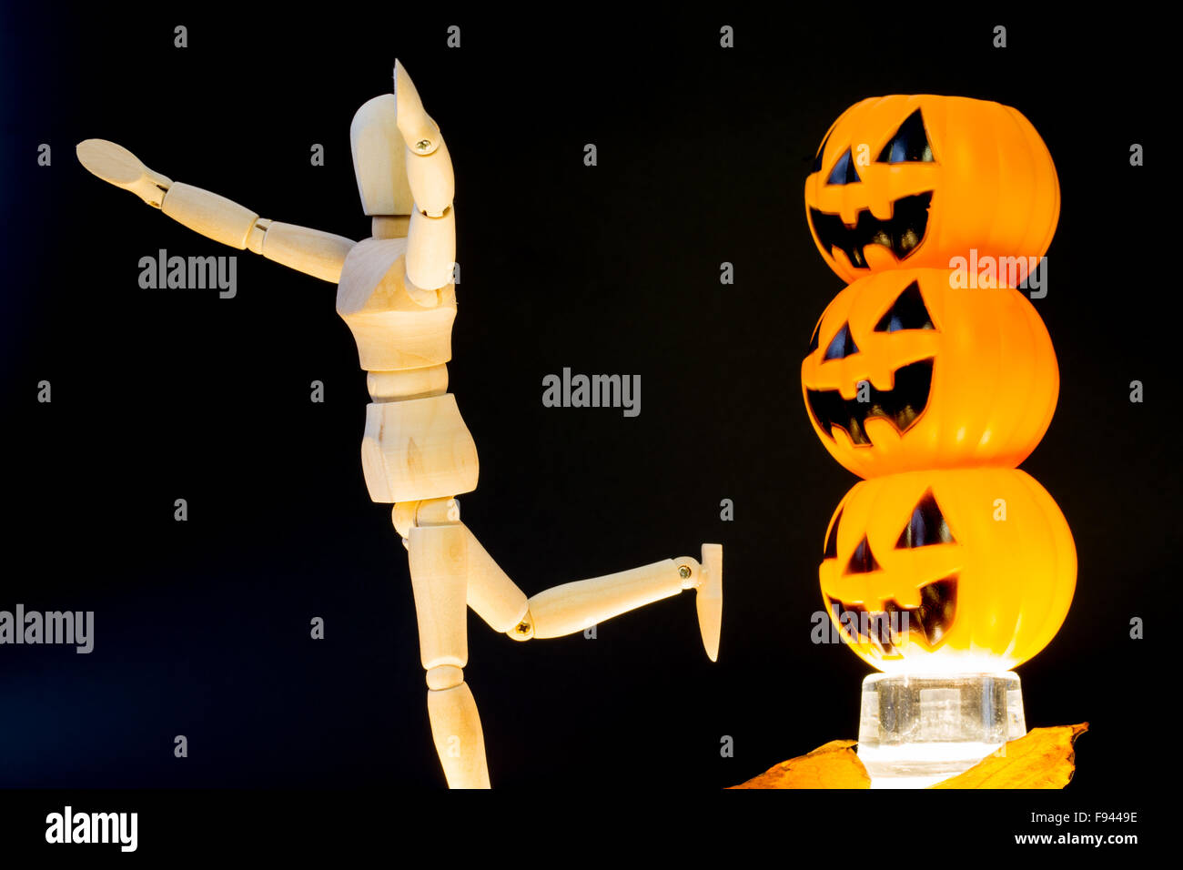 Three plastic pumpkins scare wooden puppet away Stock Photo - Alamy
