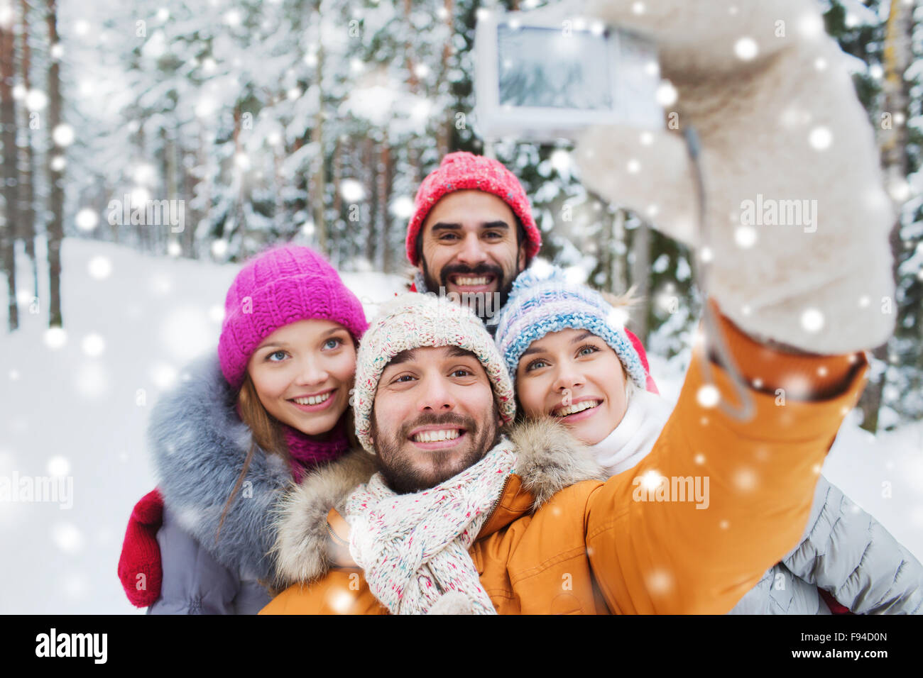 smiling friends with camera in winter forest Stock Photo - Alamy