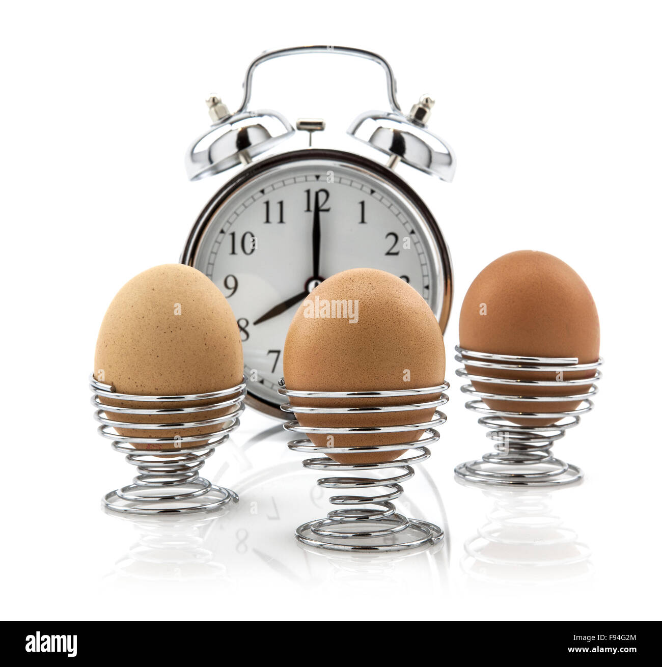 Three Eggs in egg cups with old clock on white background Stock Photo ...