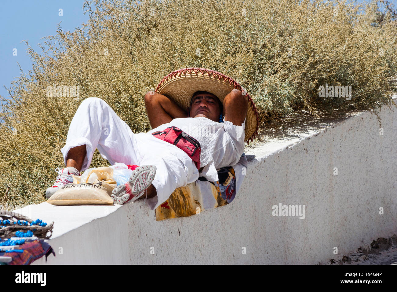 Cyclades, Santorini. Greek man laying on whitewashed wall asleep in the ...