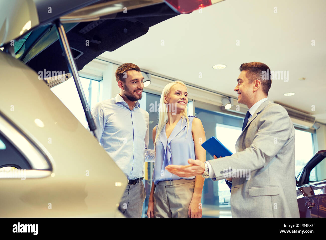 happy couple with car dealer in auto show or salon Stock Photo - Alamy
