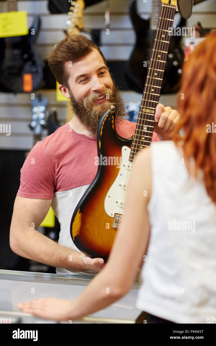 assistant showing customer guitar at music store Stock Photo - Alamy