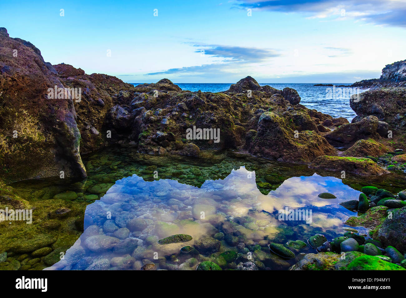 Stone Coast of Atlantic Ocean with Sky Reflection in water on Canary ...