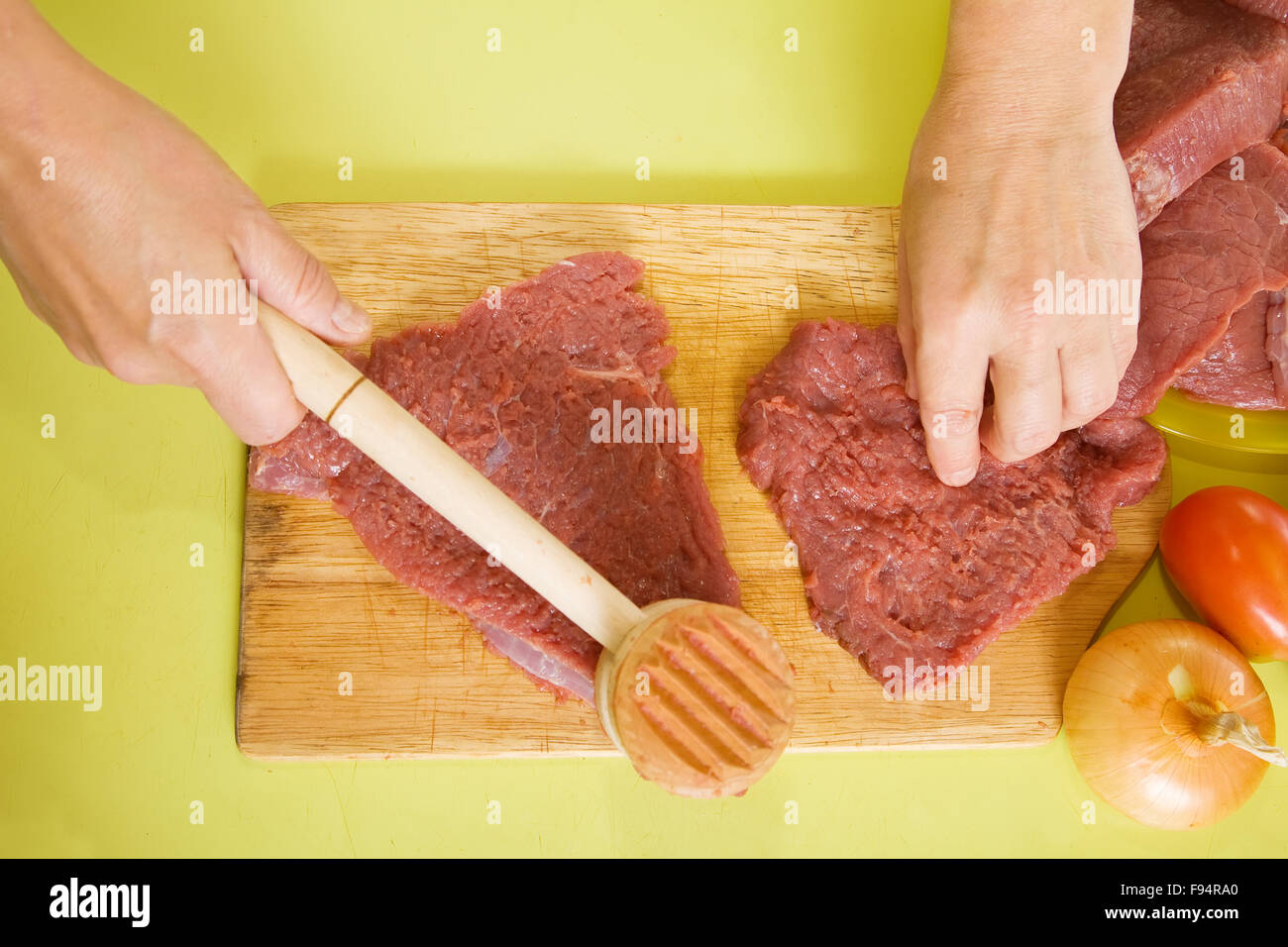 Closeup of cook hands making tenderized steak with meat hammer. One of ...