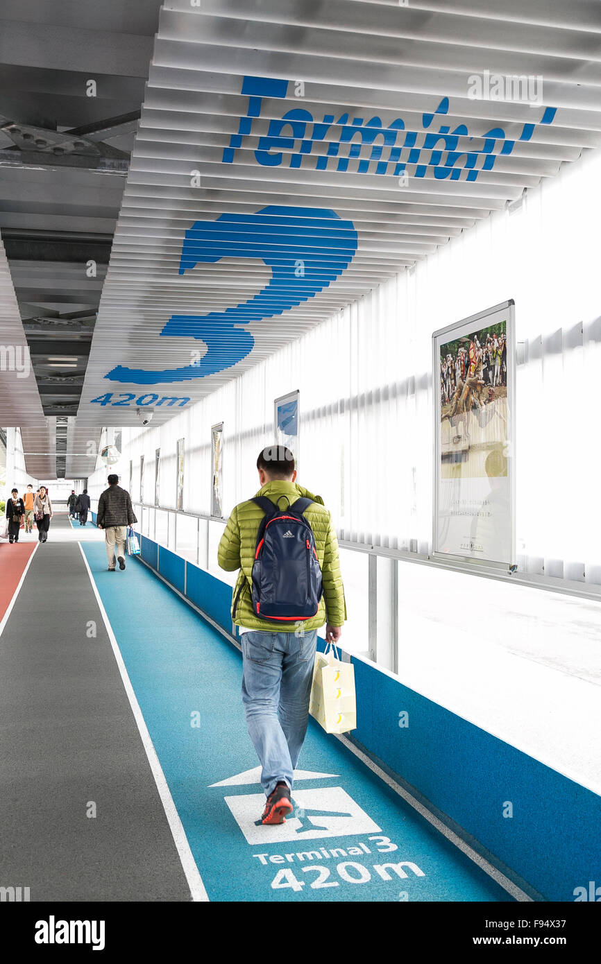 Passengers walk on a running track to the new Terminal 3 at Narita ...