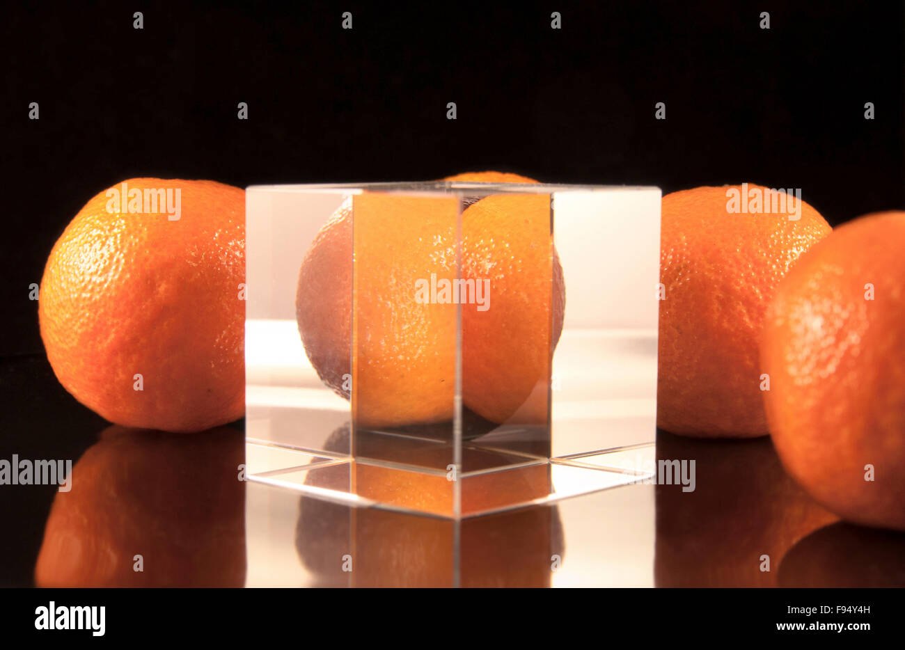 Tangerines with a glass cube on the black background Stock Photo - Alamy