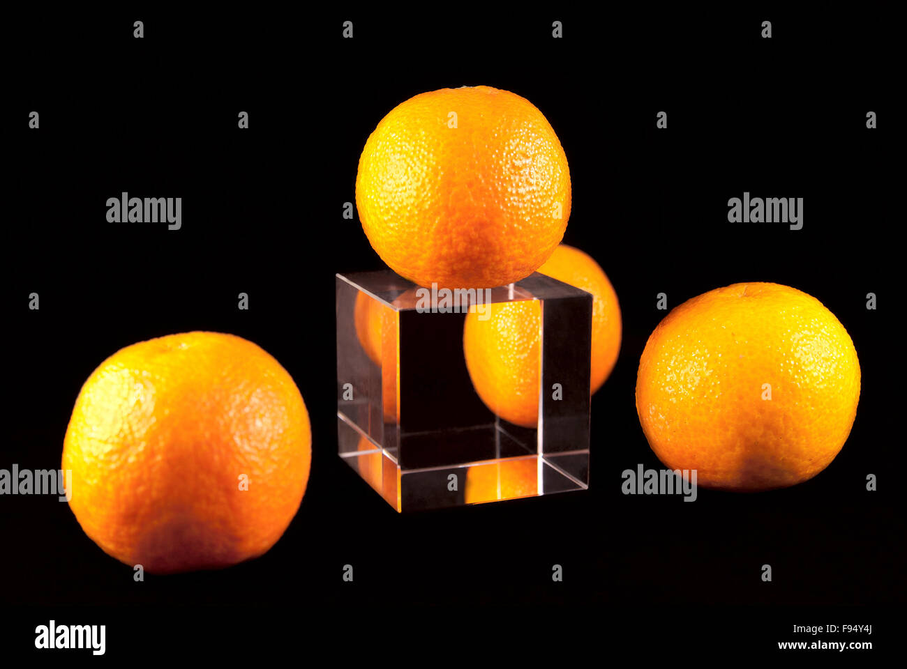 Tangerines with a glass cube on the black background Stock Photo - Alamy