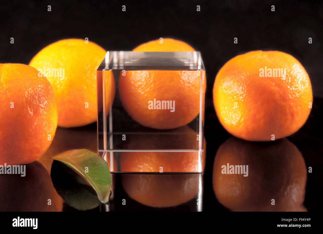 Four tangerines with a glass cube Stock Photo - Alamy