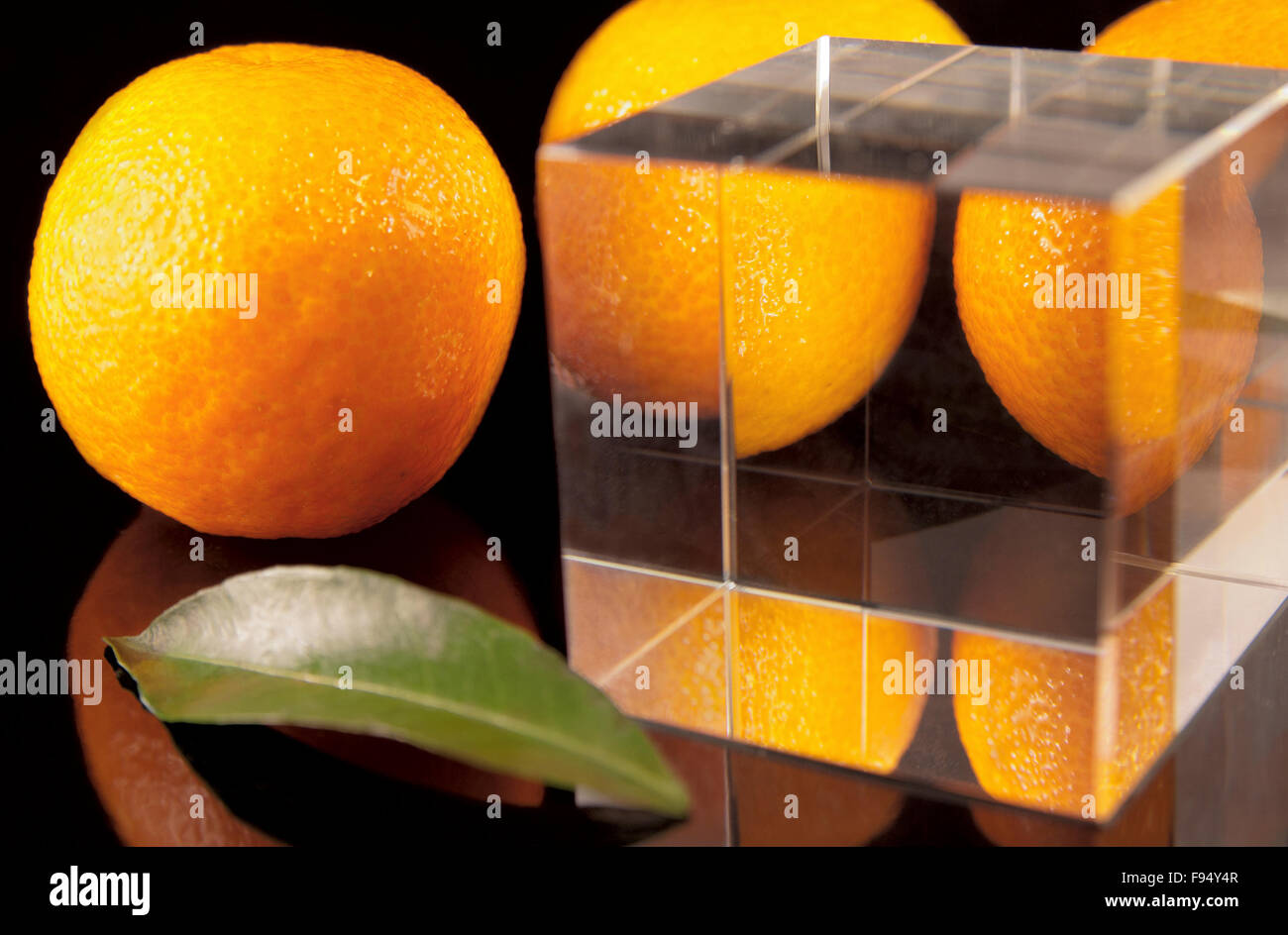 Three tangerines with a glass cube Stock Photo - Alamy