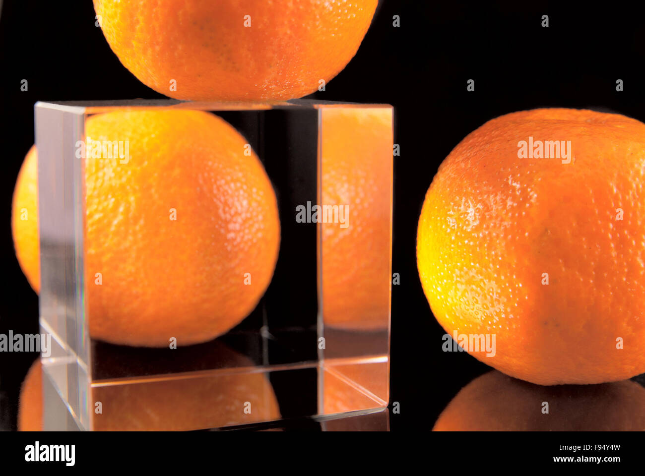Tangerines with a glass cube on the black background Stock Photo - Alamy