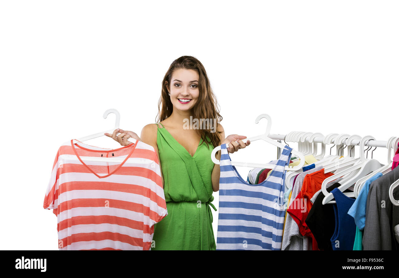 Portrait of a beautiful young woman near rack with hangers deciding ...
