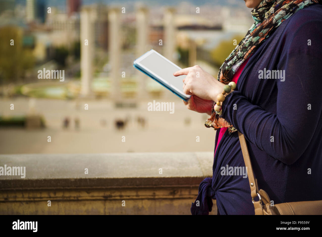 Pretty young female tourist using digital tablet and enjoying the view ...