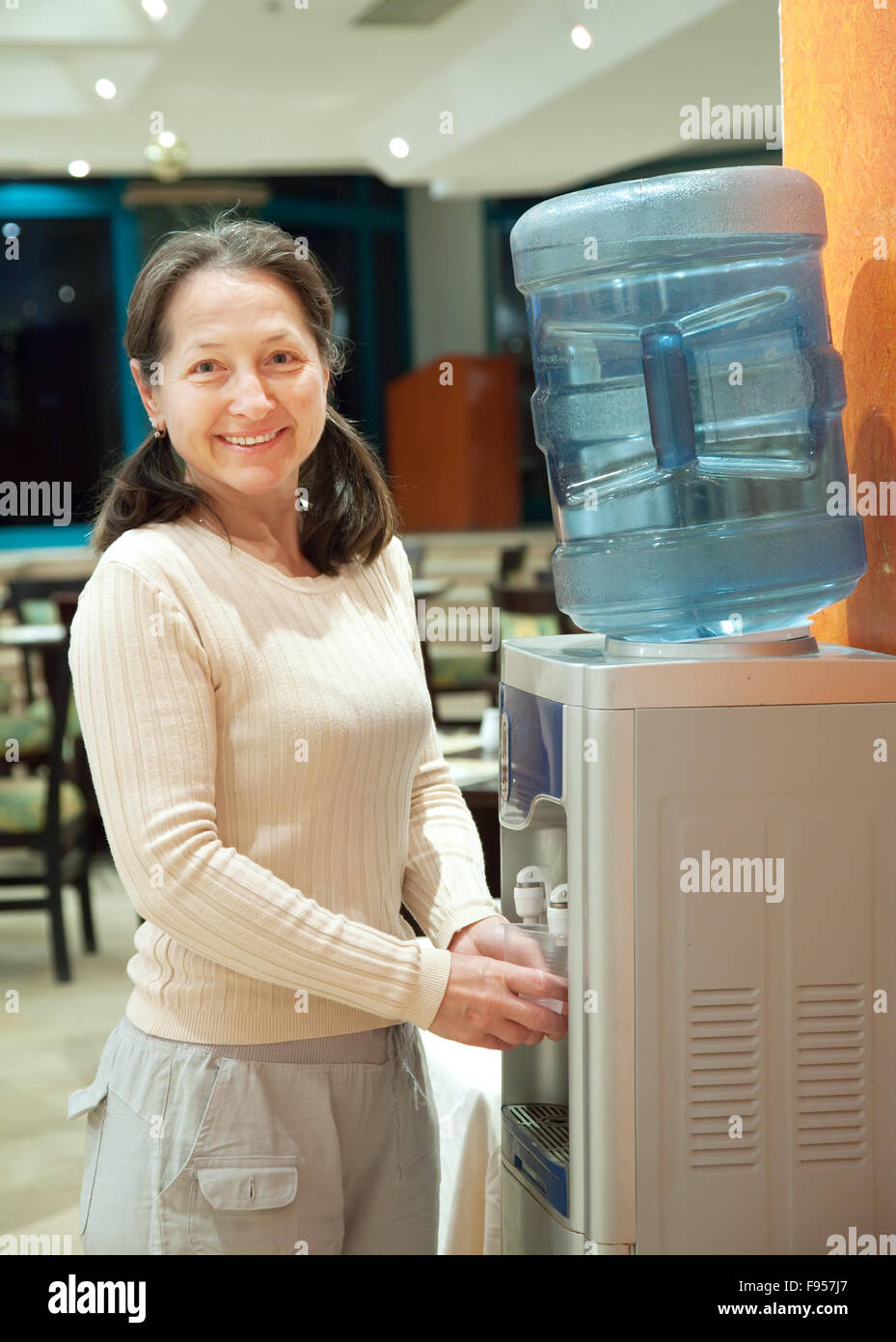 Woman pours water from water cooler Stock Photo - Alamy
