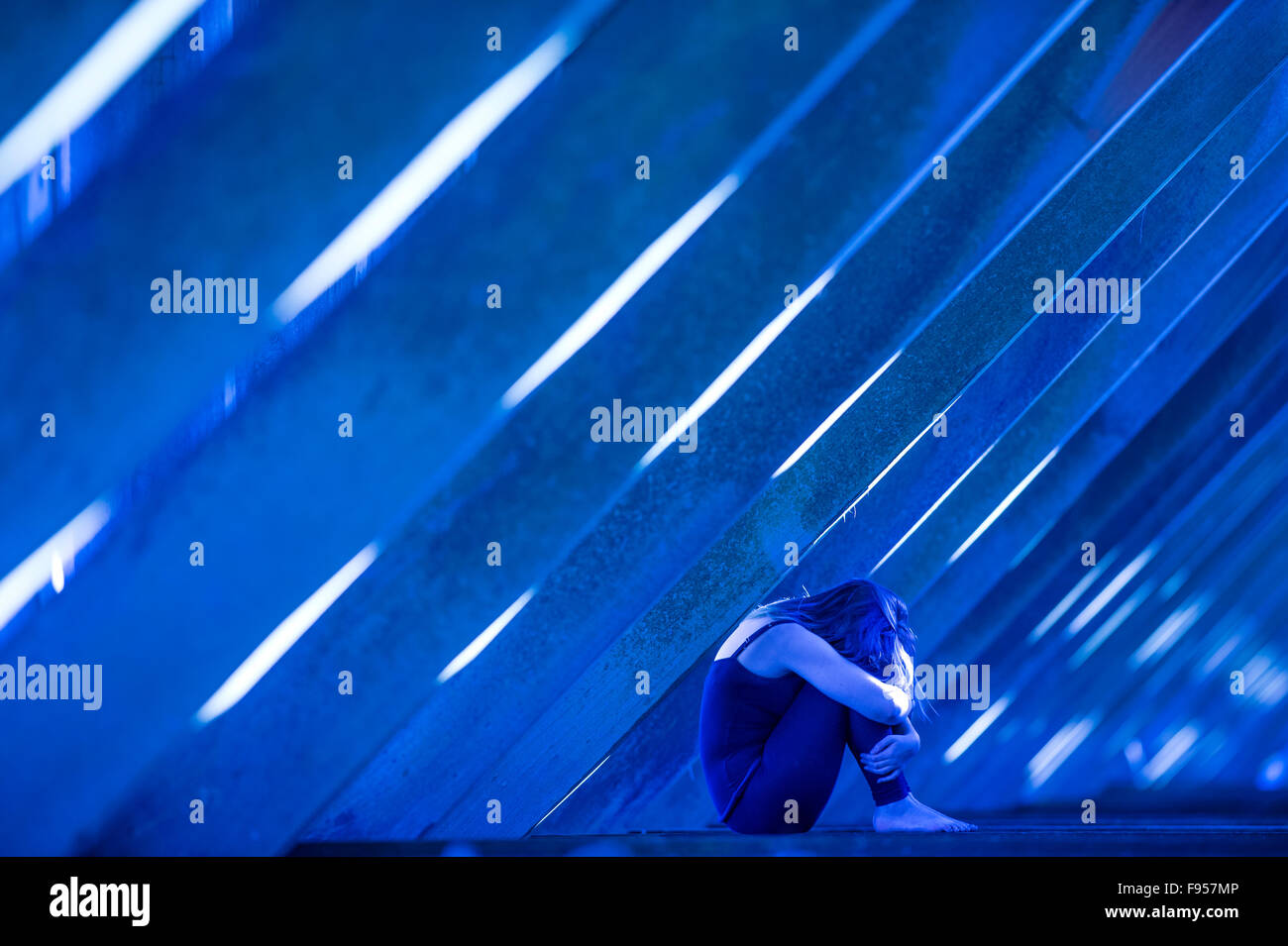 Loneliness and depression - a sad young woman sitting crouching holding ...
