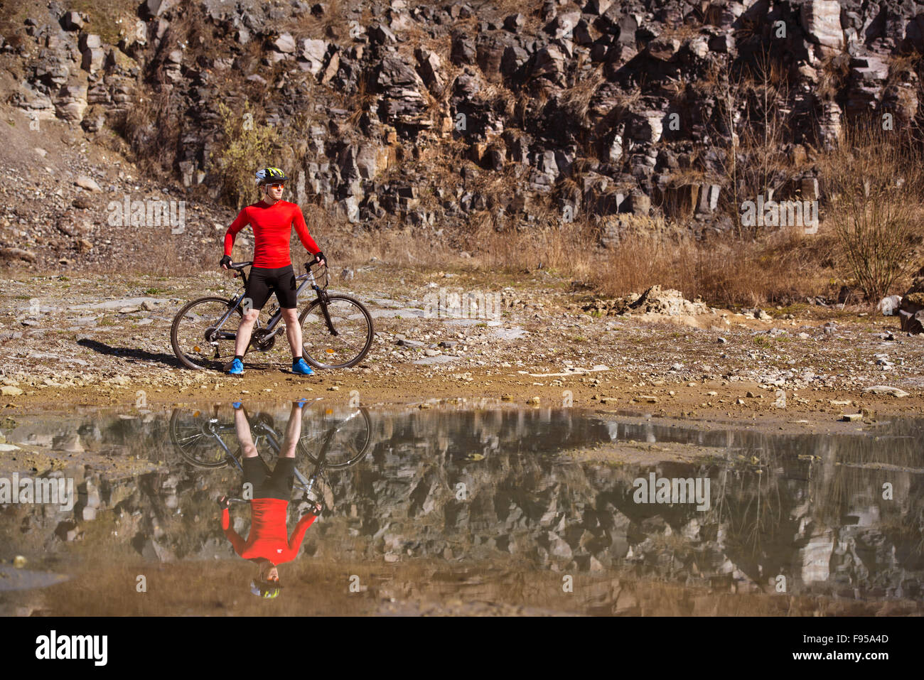 Cyclist man standing with his bike is reflecting in water puddle Stock ...