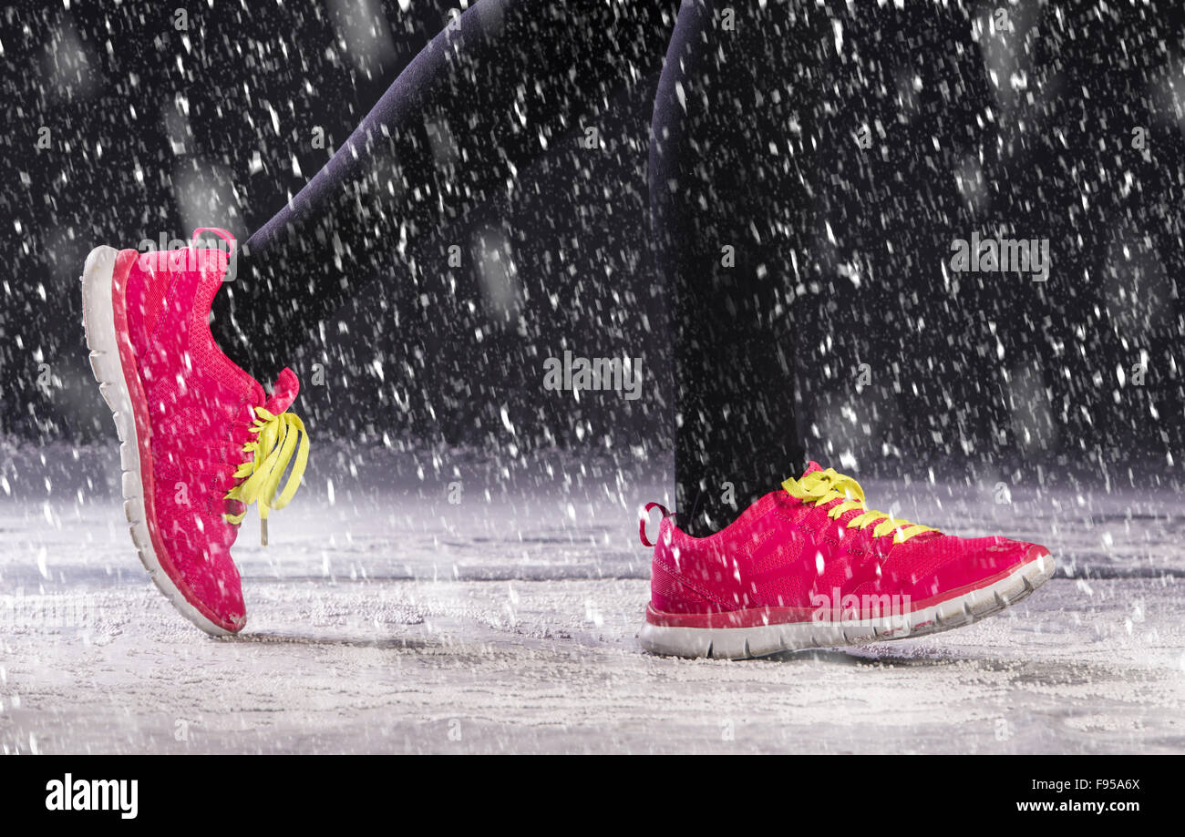 Athlete woman is running during winter training outside in cold snow ...