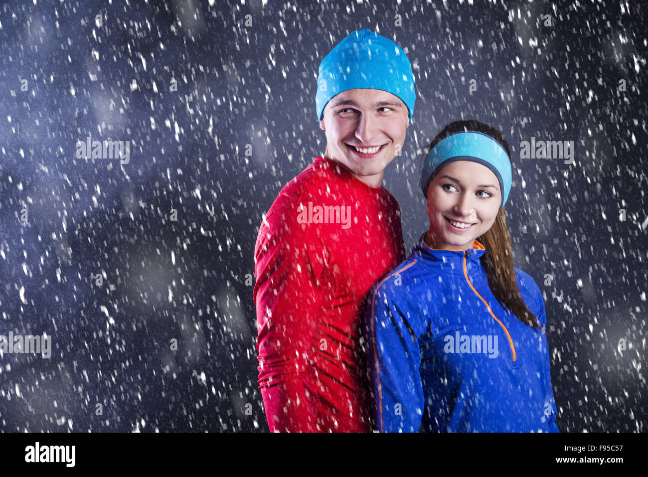 Young fitness athletes are standing outside in cold winter night. Snow ...