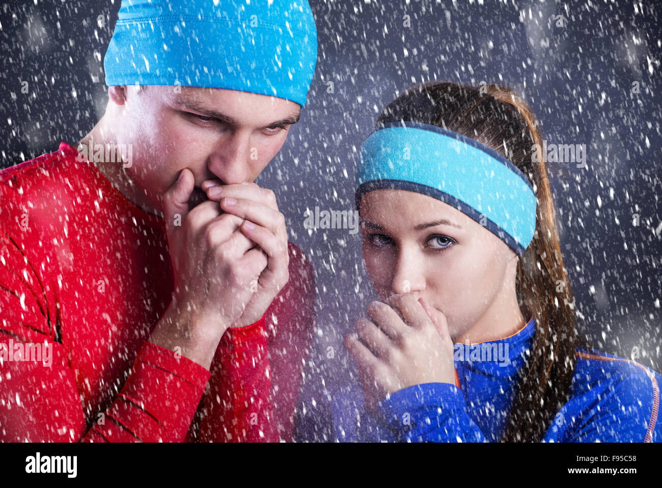 Young fitness athletes are standing outside in cold winter night. Snow ...