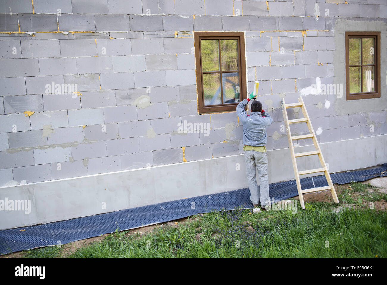 Man applying foam sealant with caulking gun to insulate the window ...