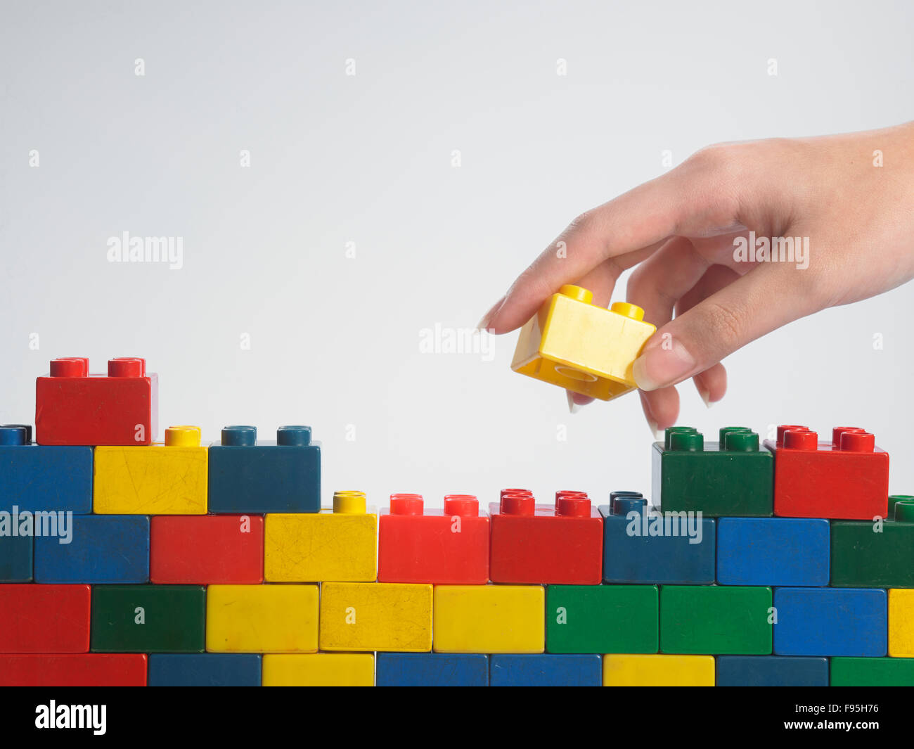 hand stack up lego set as a wall on white background Stock Photo - Alamy