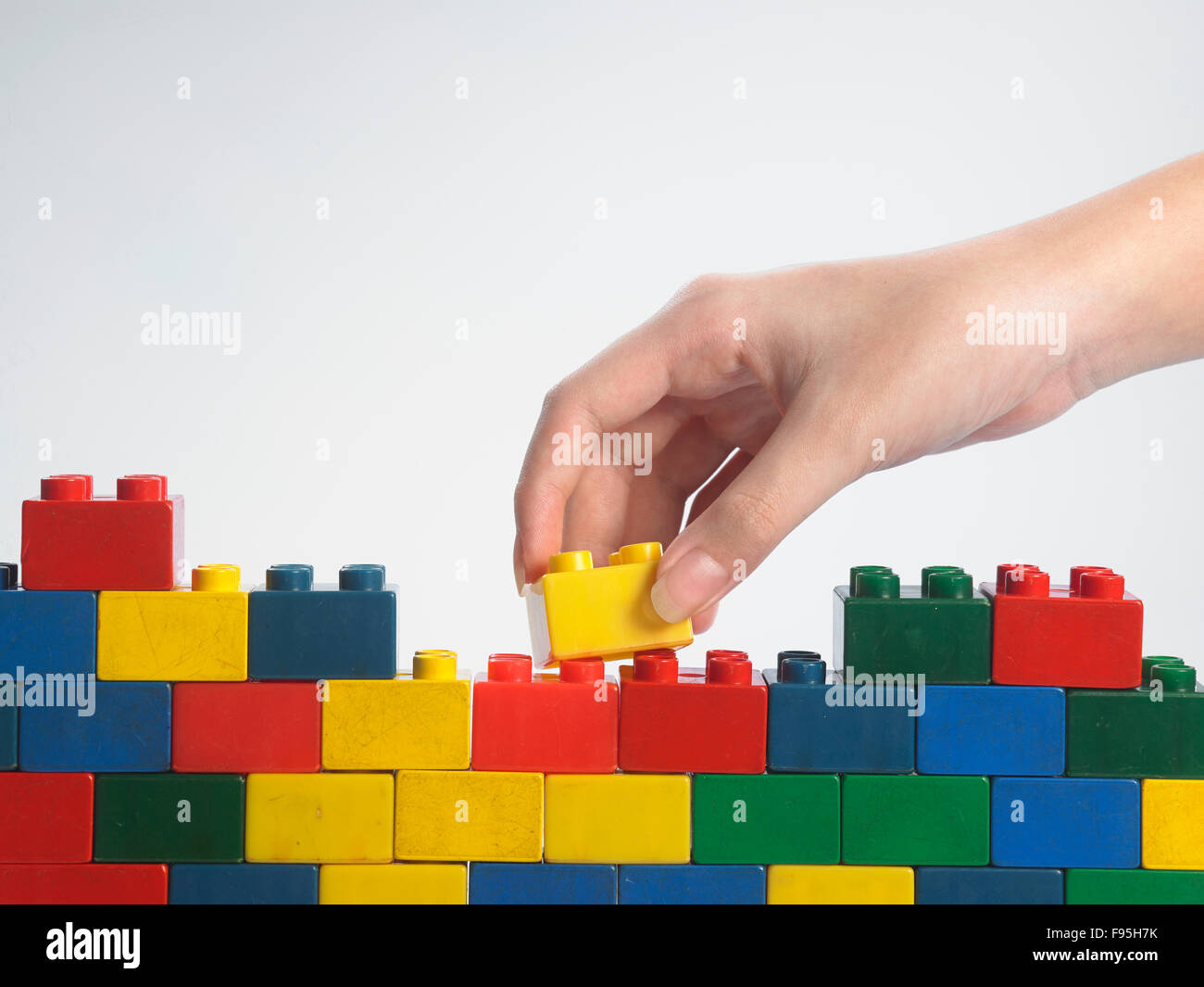hand stack up lego set as a wall on white background Stock Photo - Alamy