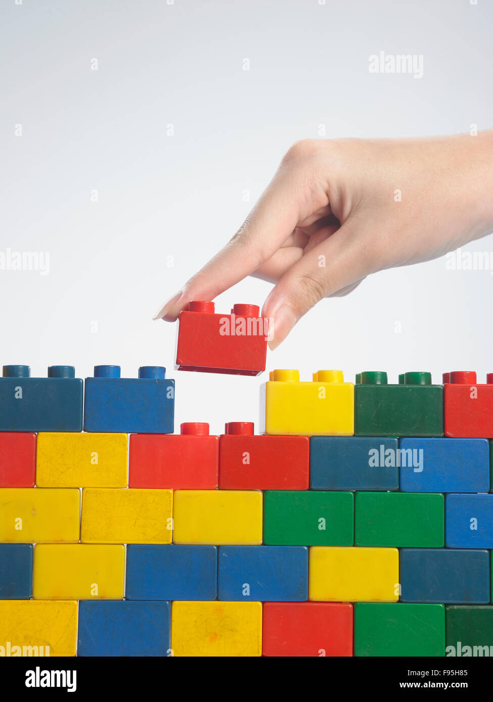 hand stack up lego set as a wall on white background Stock Photo - Alamy