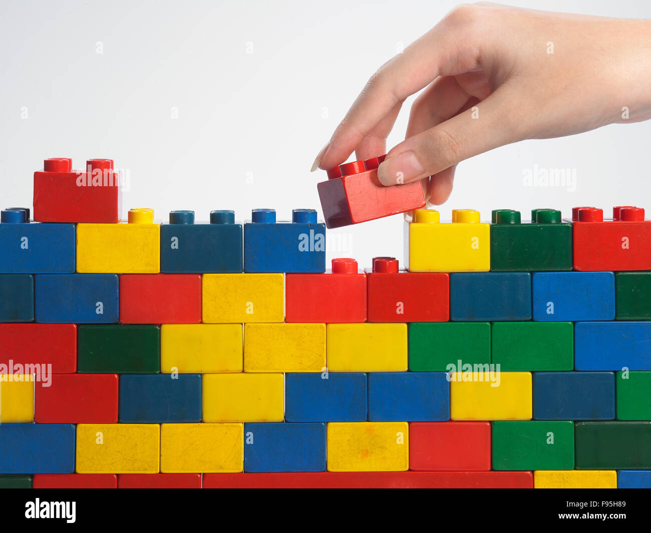 hand stack up lego set as a wall on white background Stock Photo - Alamy