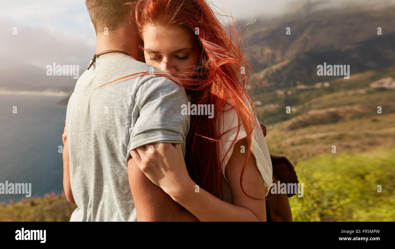 Close up shot of young woman hugging her boyfriend. Young couple in love embracing outdoors ...