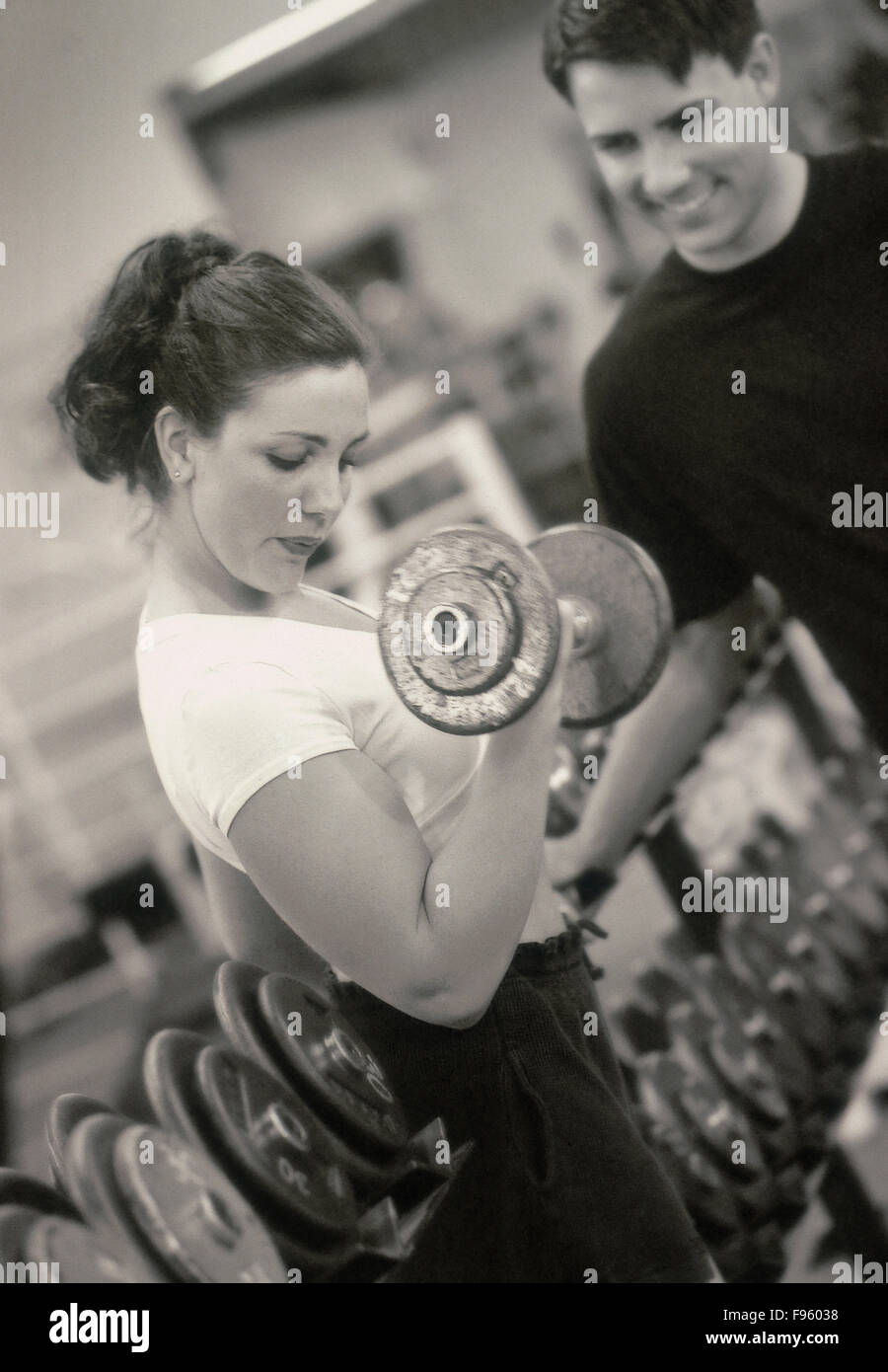 Caucasian female and male lifting weights in fitness club (Model ...