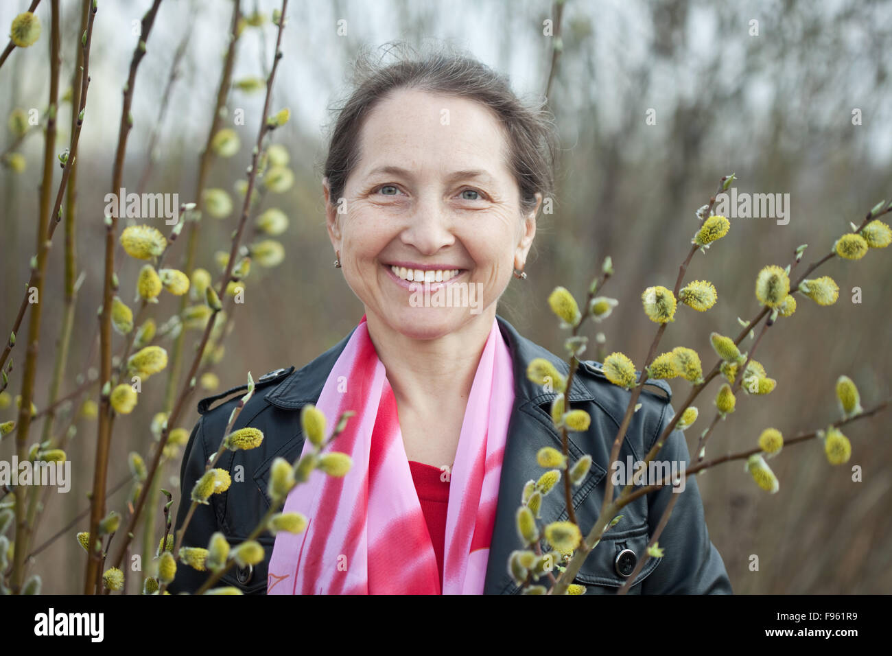 portrait of happy mature woman against spring willow branches with buds ...