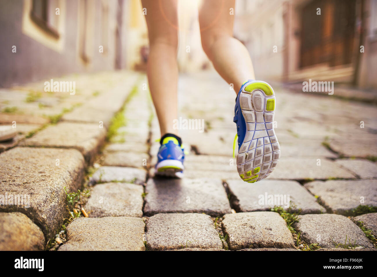 Female runner running on tiled pavement in city center, closeup on ...
