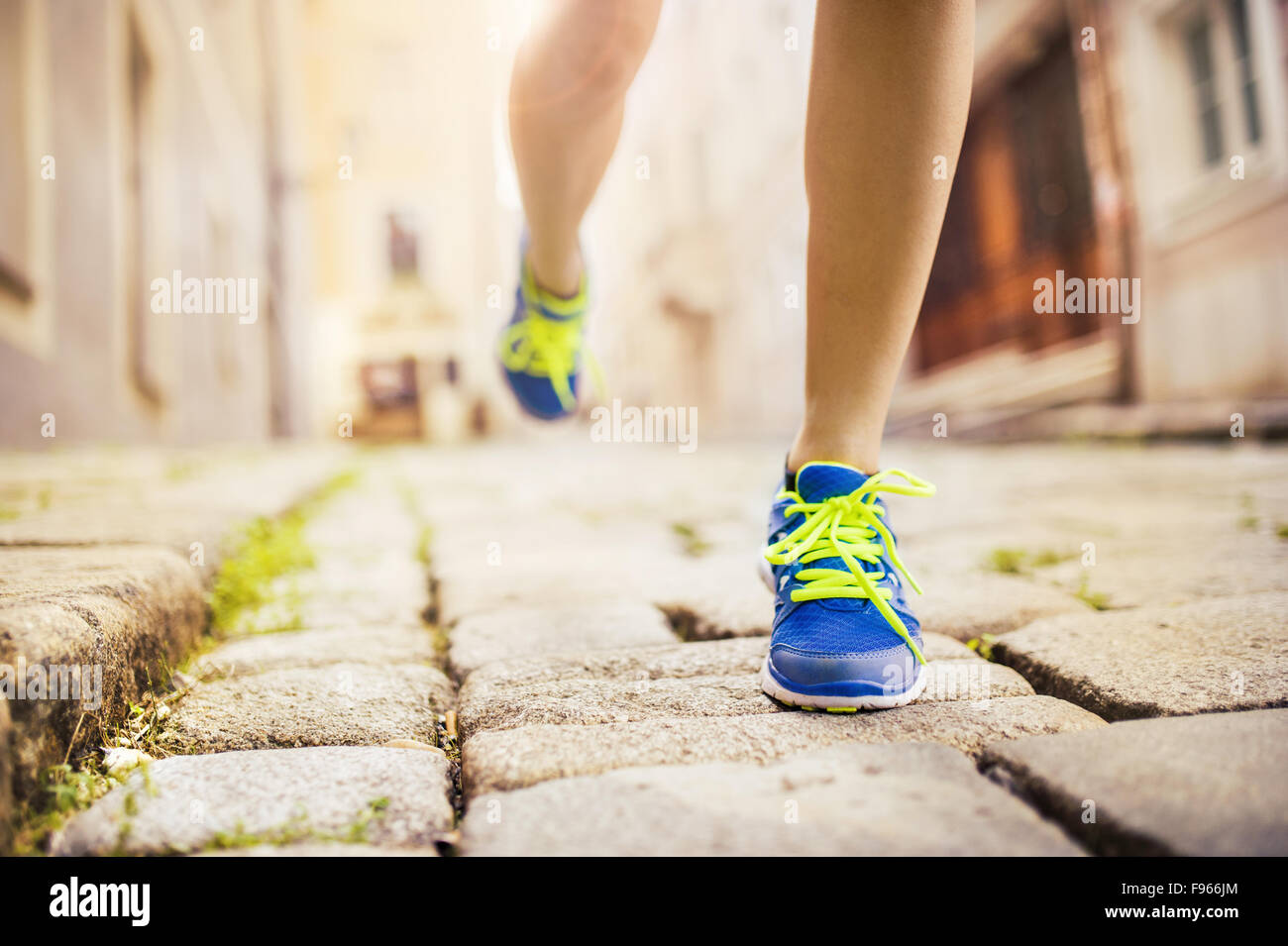 Female runner running on tiled pavement in city center, closeup on ...